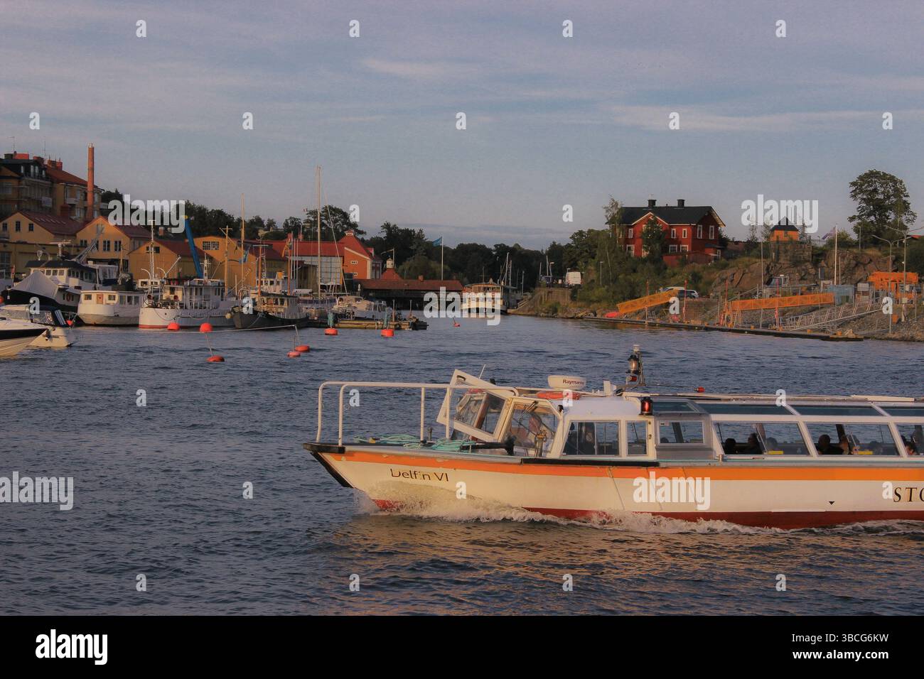 Passenger ferry Delfin VI cruising through a scenic marina at sunset in ...