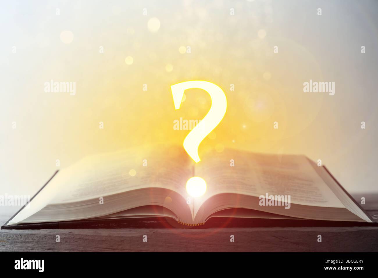 Question mark and magic lights above open book on table against light ...