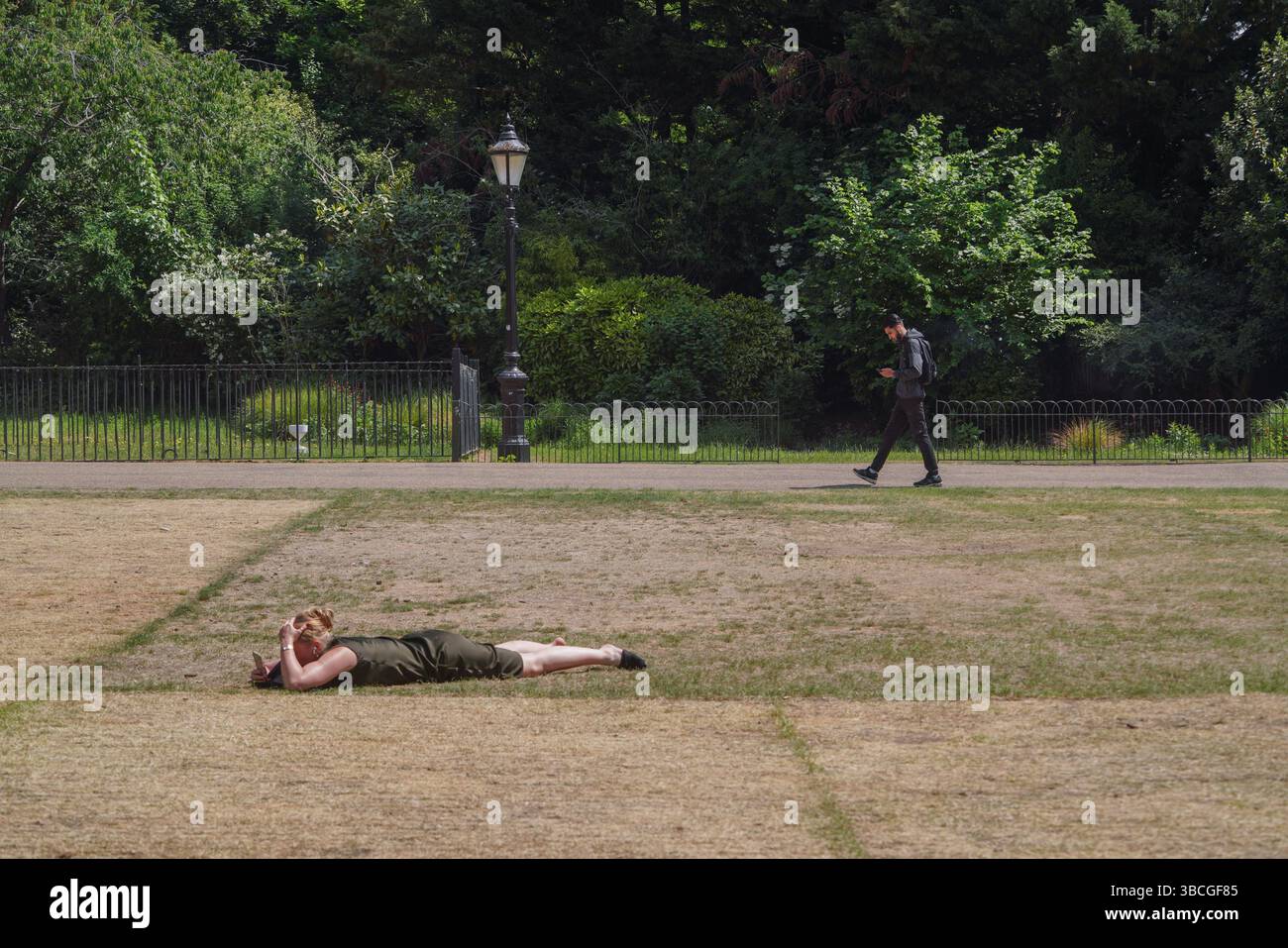 London, UK. 20 May 2025 A woman relaxing on the parched grass in Saint ...