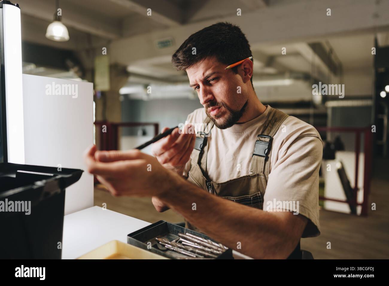 Craftsman focusing intently on tool maintenance in workshop environment ...