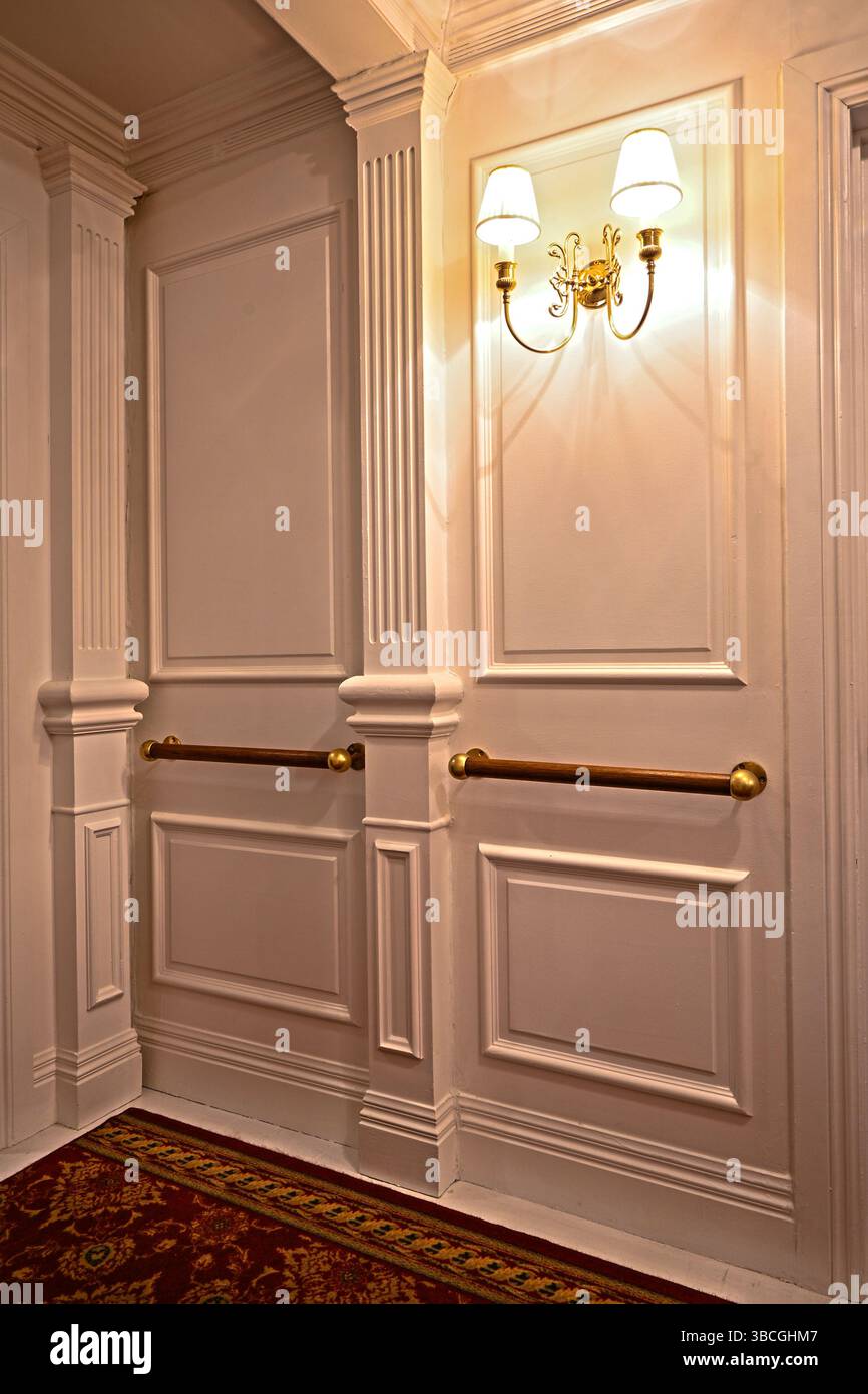 Classic interior design featuring white wall paneling, golden handrails ...