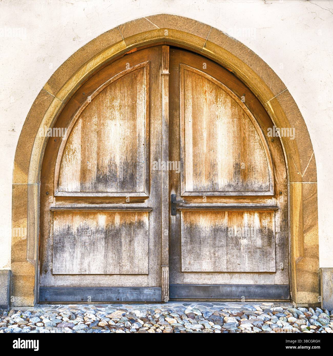 horizontal view of a massive winged wooden door in a stone wall with a ...
