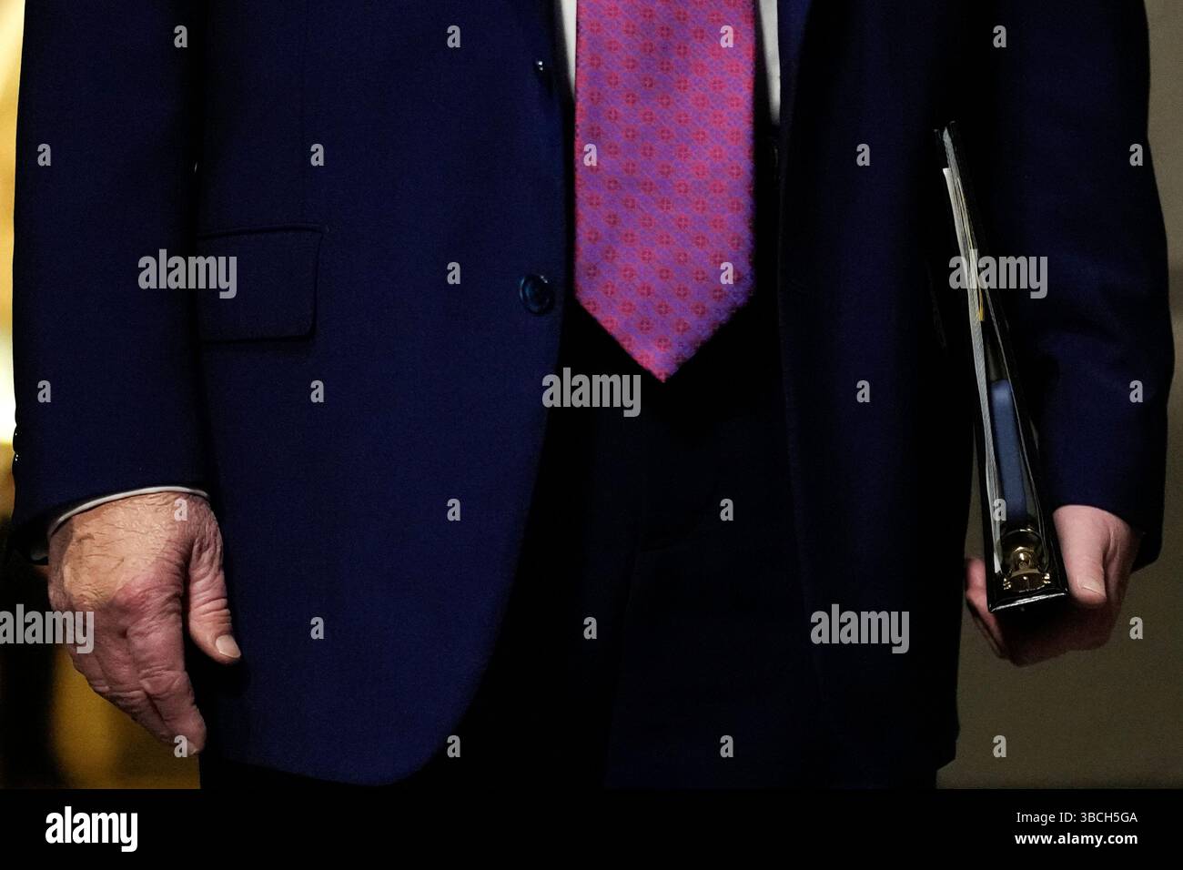 President Donald Trump holds a binder with a cell phone inside while ...