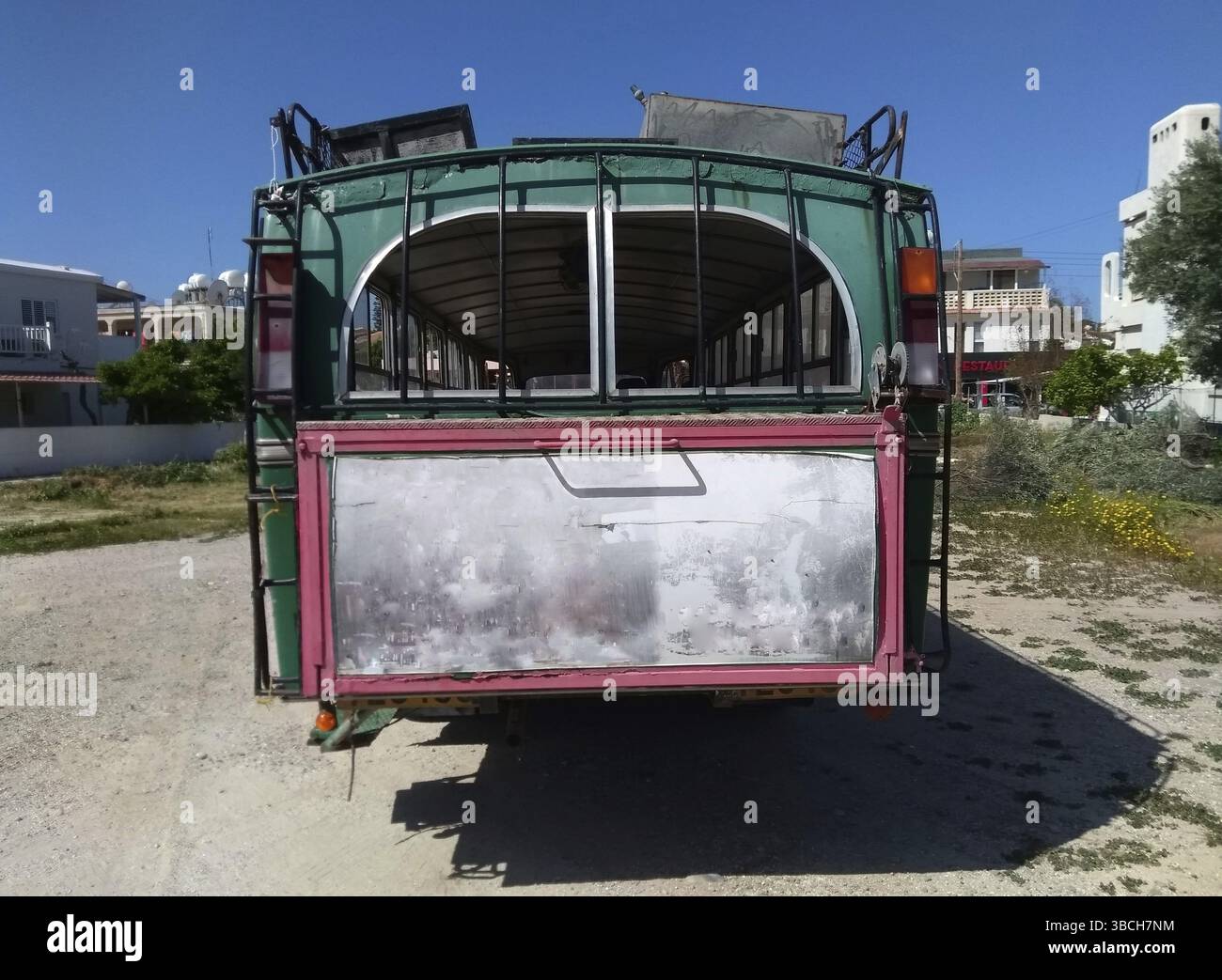 Rear view of an old rusting green painted bus with roof rack parked in ...