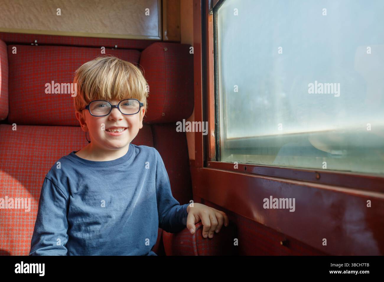 Boy sits inside train cabin smiling at camera from a plush seat Stock ...