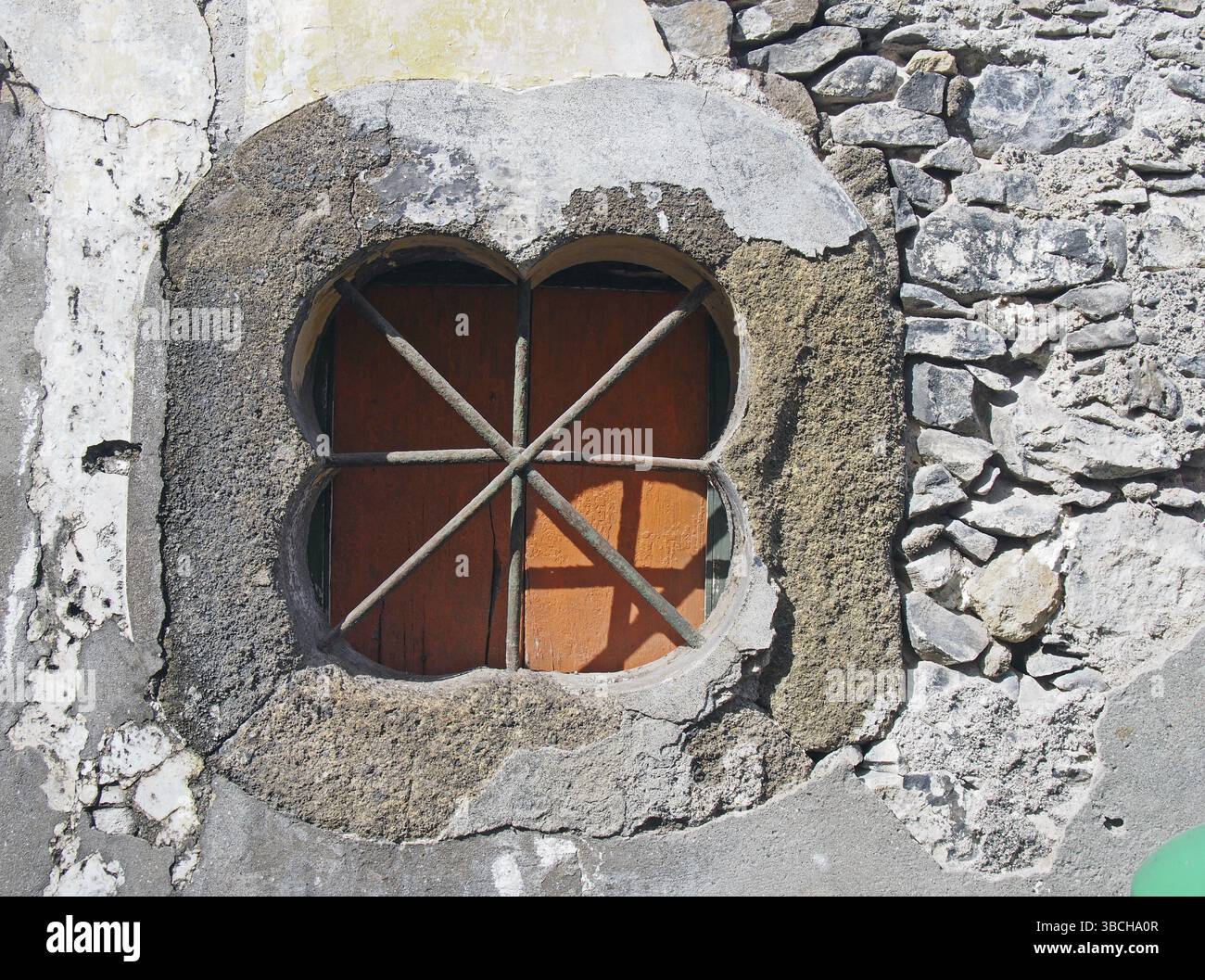 And ancient stone oblong shaped window with crossed bars with an orange ...