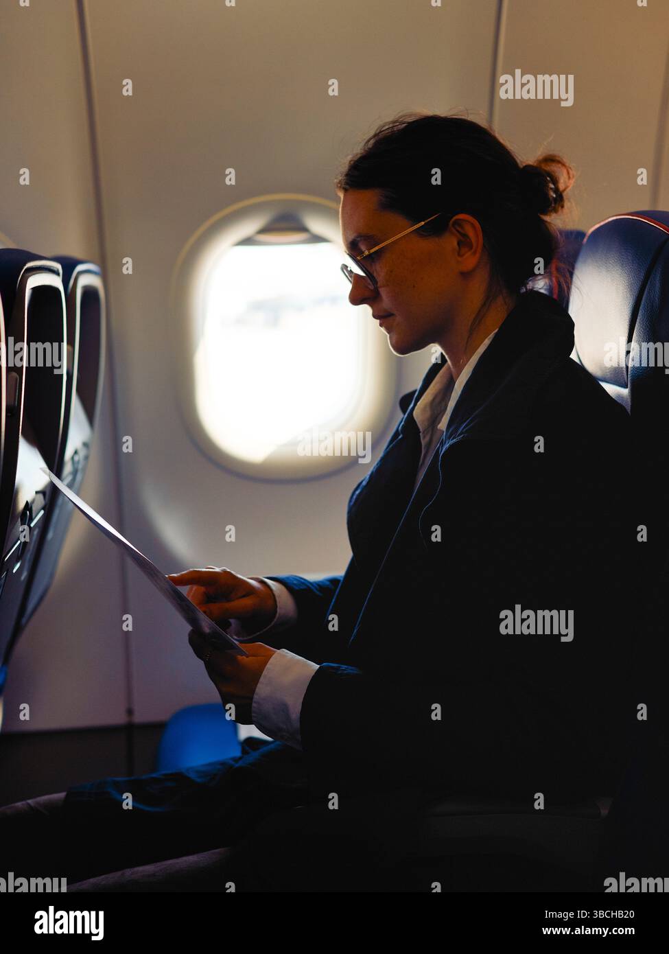 Woman reading security instructions while seated on an airplane, calm ...
