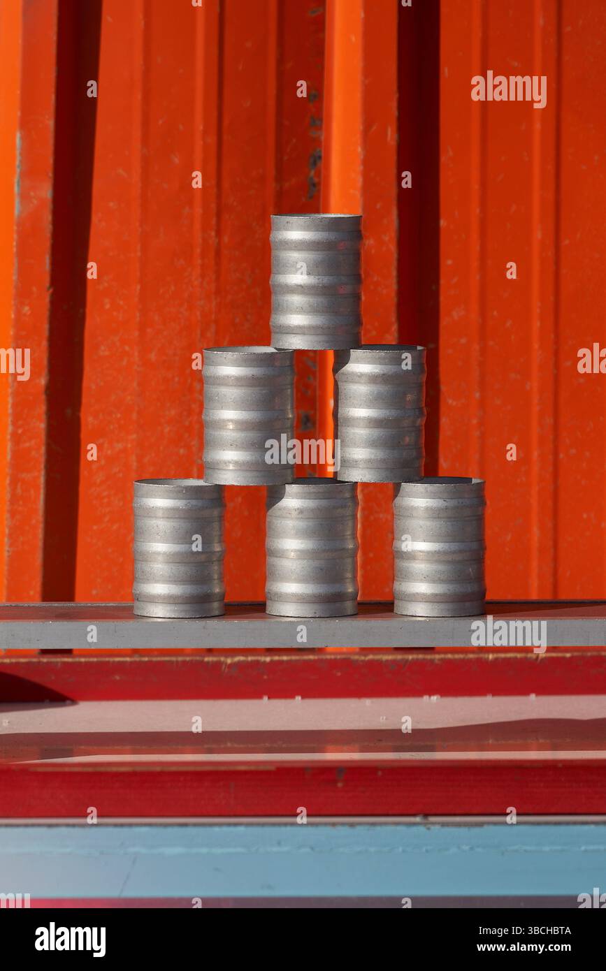 Six silver cans stacked in a pyramid against vibrant orange and red ...