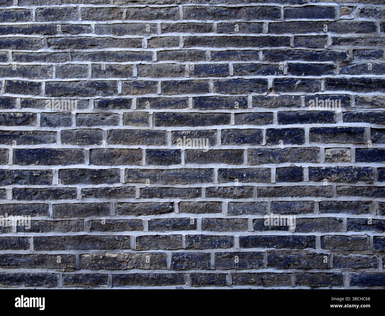An old wall made of black stone bricks with grey cement Stock Photo - Alamy