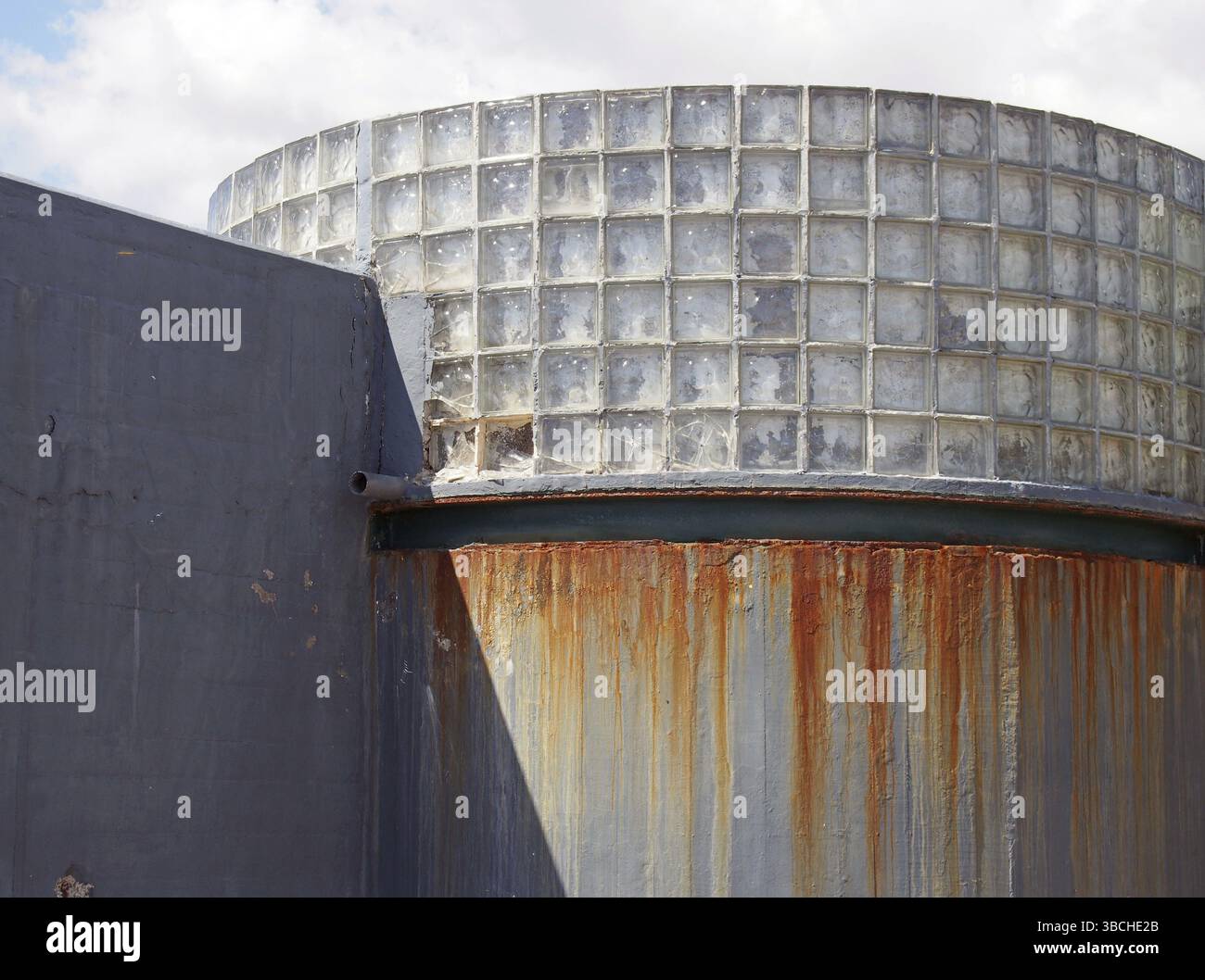 An old building with a curved grey concrete wall with rows of square ...