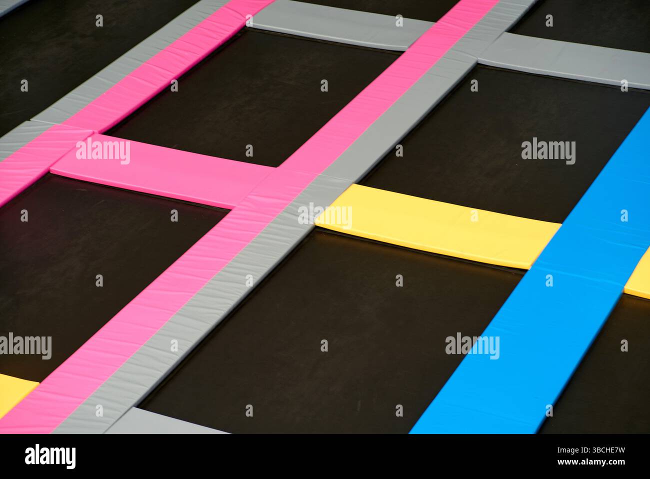Colorful trampoline grid with pink, yellow, gray, and blue stripes on a ...