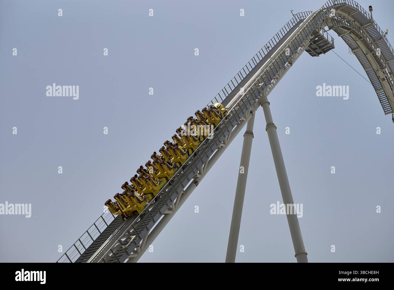 A group of people on a steep roller coaster incline against a clear ...