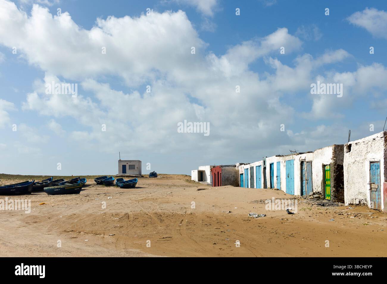Remote desert village with colorful doors and fishing boats under a ...