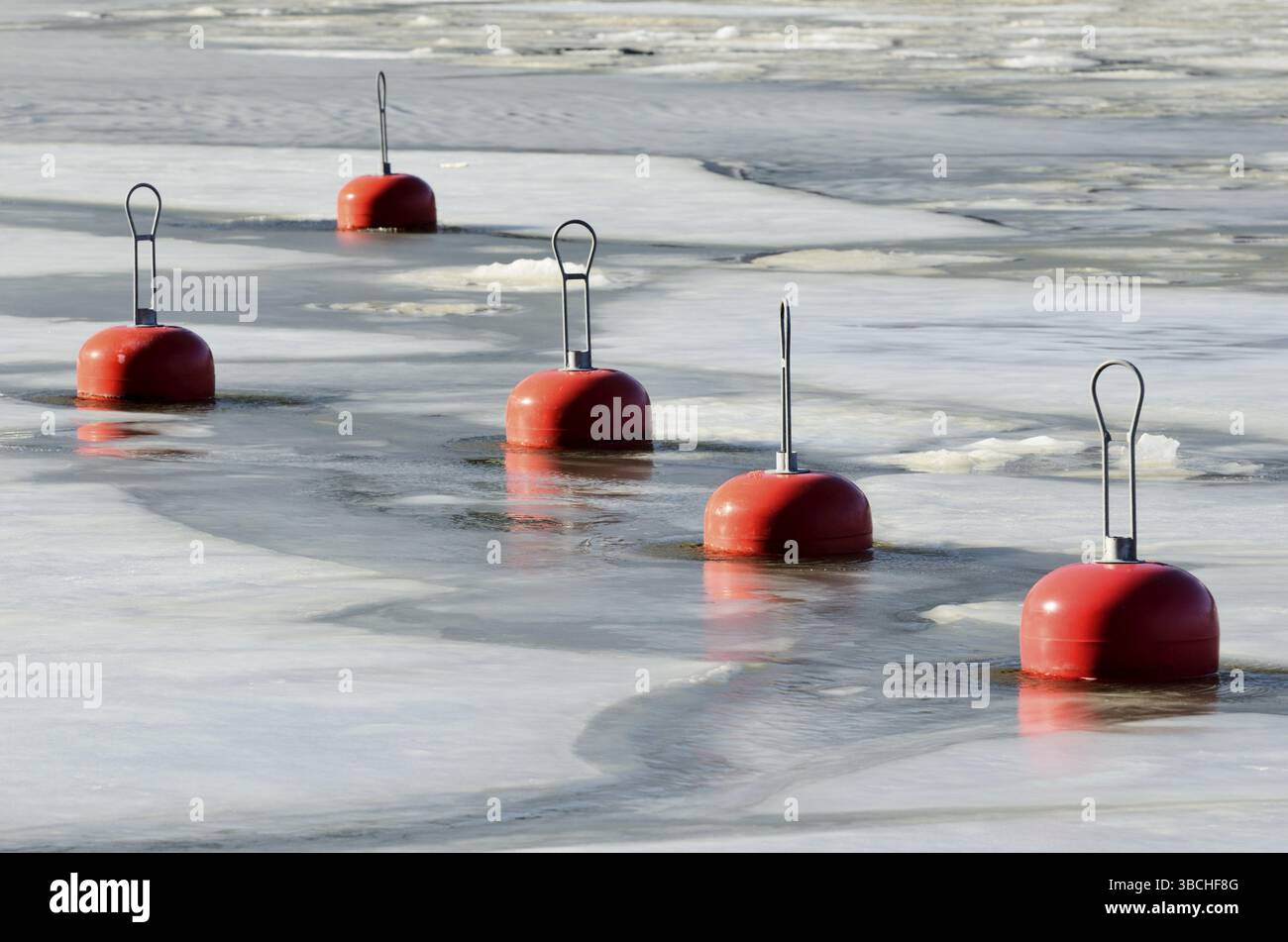 Five red buoys in the frozen water Stock Photo - Alamy
