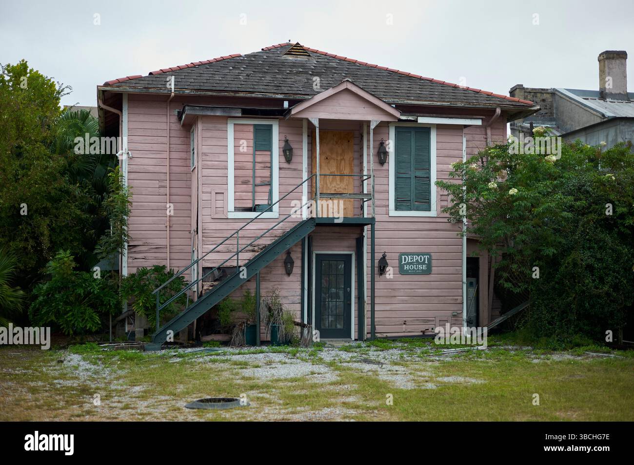 Rustic two-story wooden building with a boarded window and lush ...