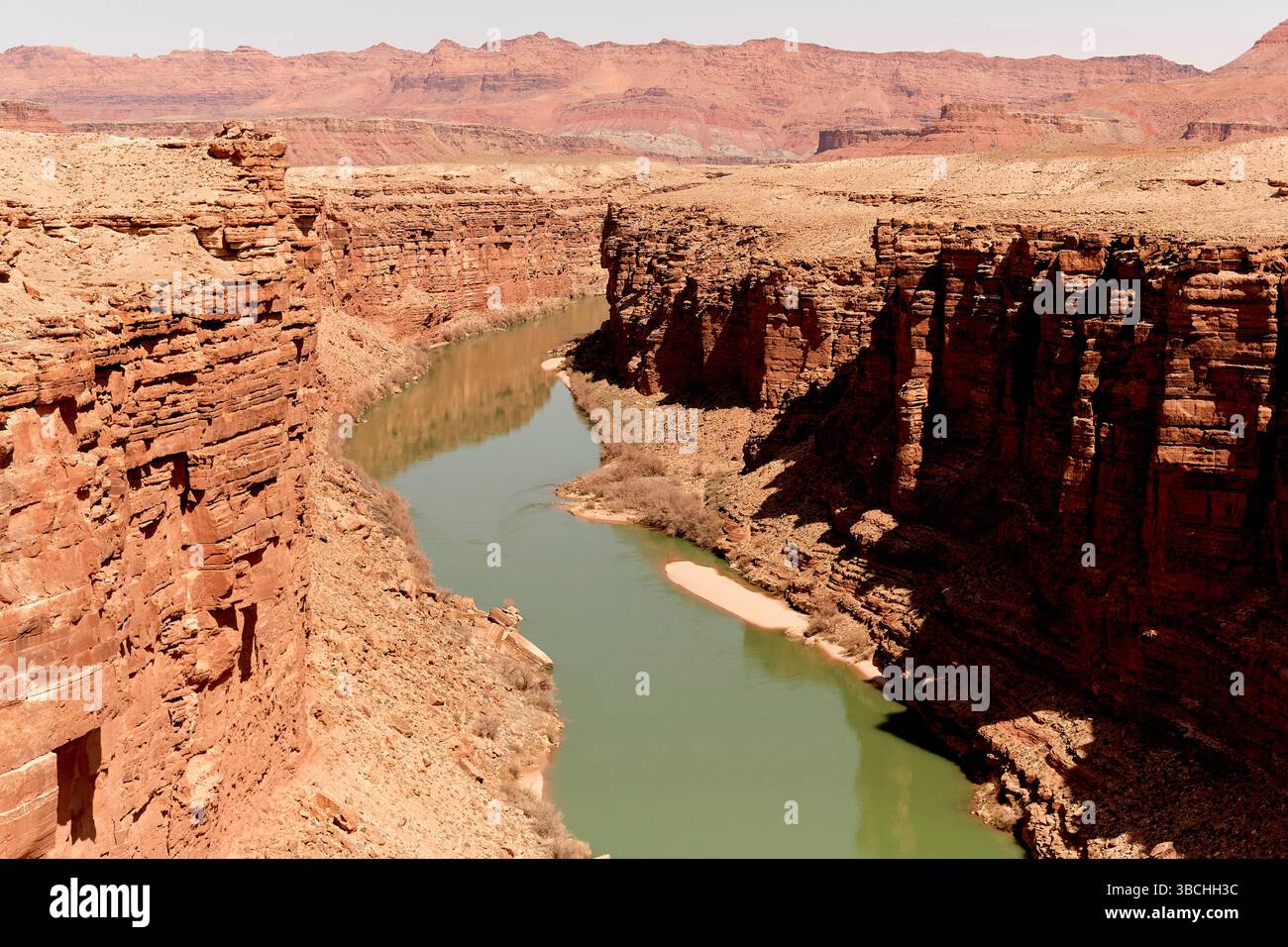 Majestic canyon with towering red rock cliffs and a winding green river ...
