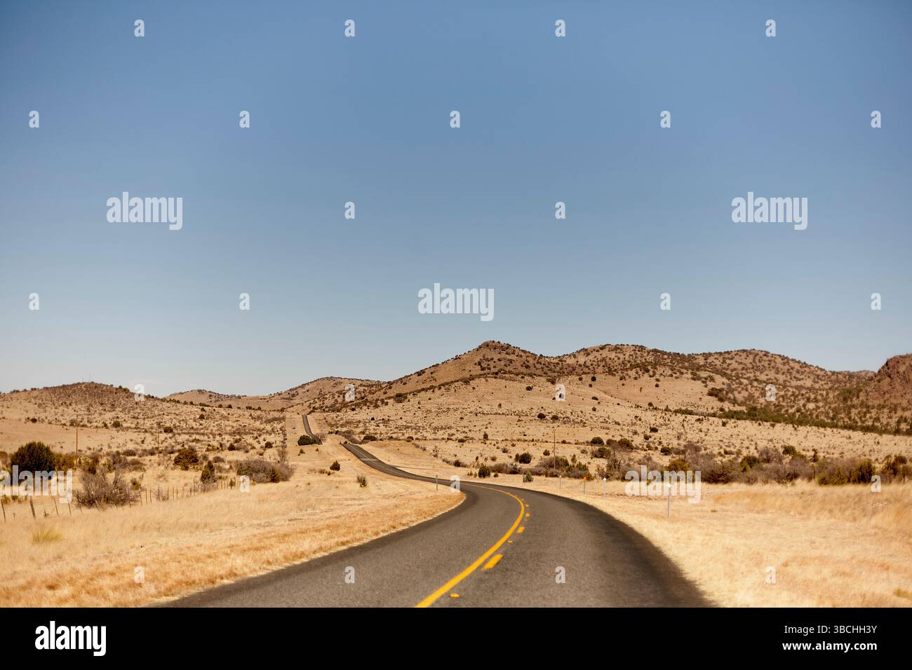 A winding road through a dry, mountainous desert landscape under a ...
