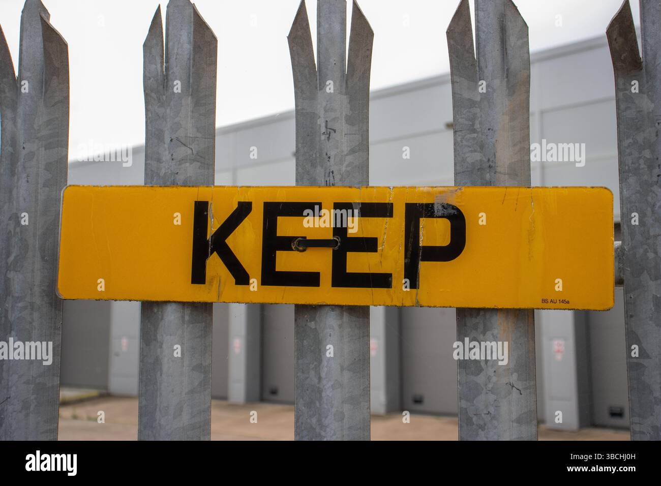 word KEEP in black letters on yellow on a grey security steel fence ...