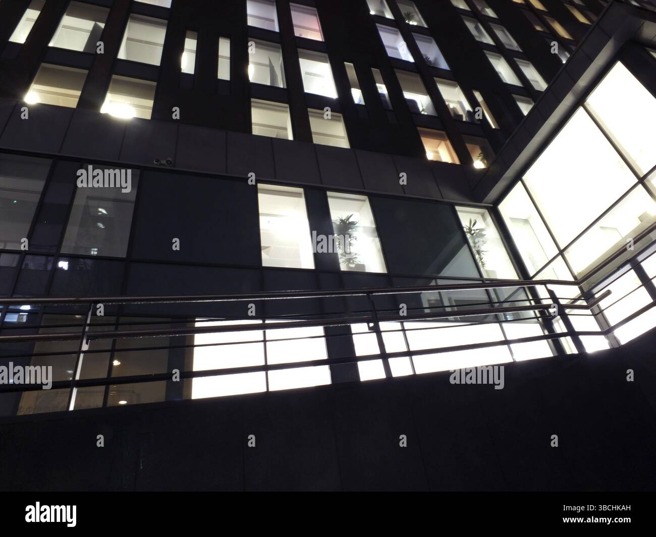 The entrance ramp and windows of a large office building brightly ...