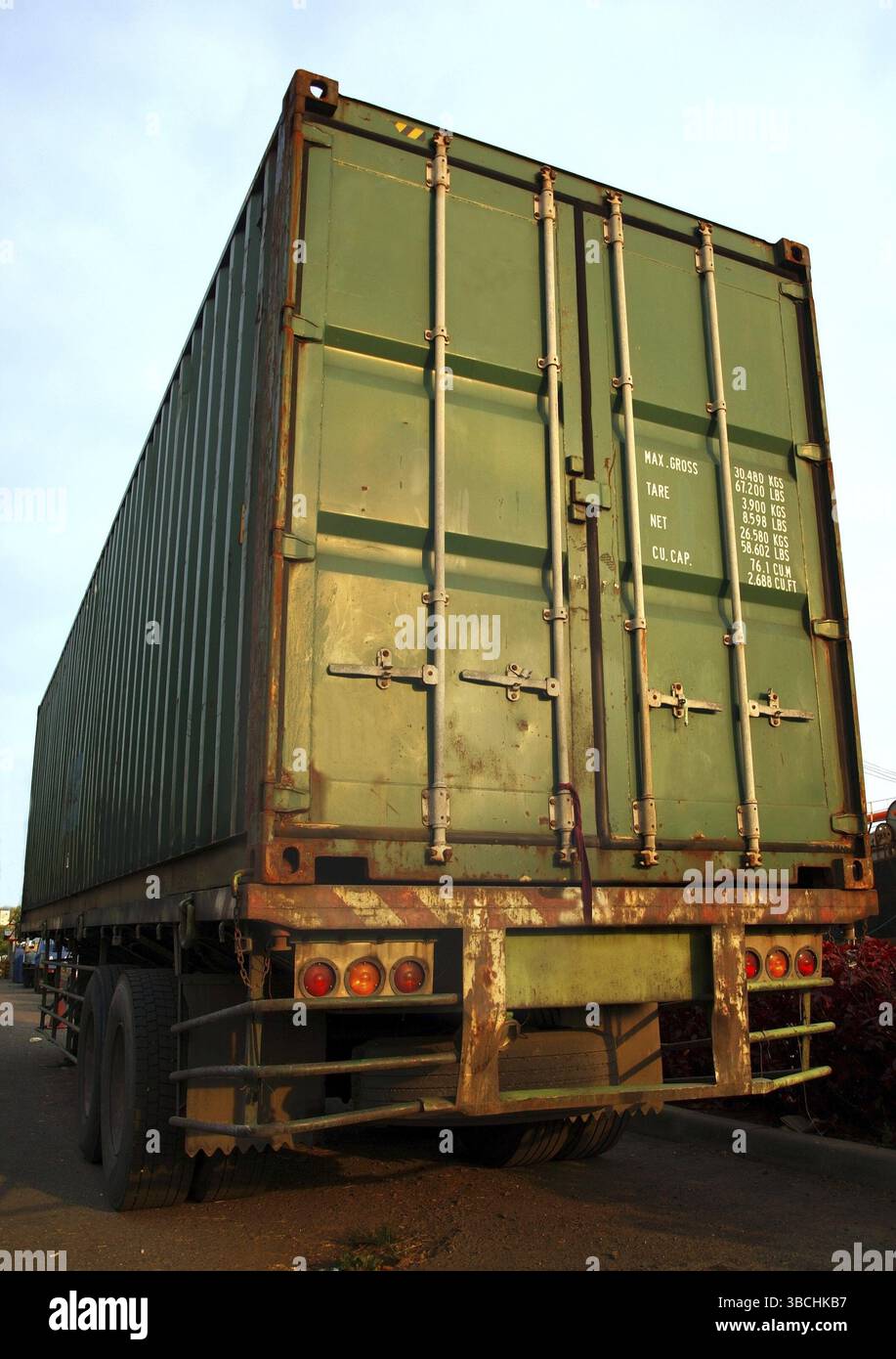 A large green shipping container is loaded onto a flatbed truck Stock ...