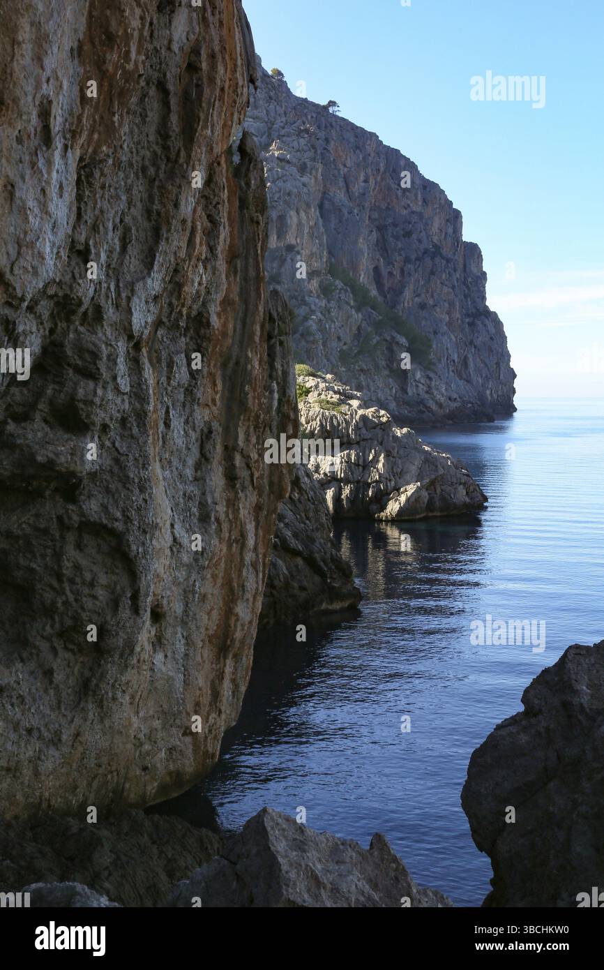 Steep cliff in blue sea in dark gorge Stock Photo - Alamy