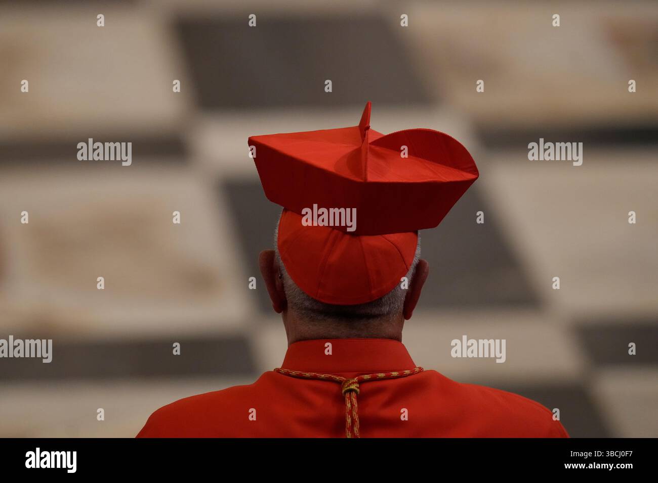 A cardinal, wearing his skull cap and biretta tricorne hat, waits for ...