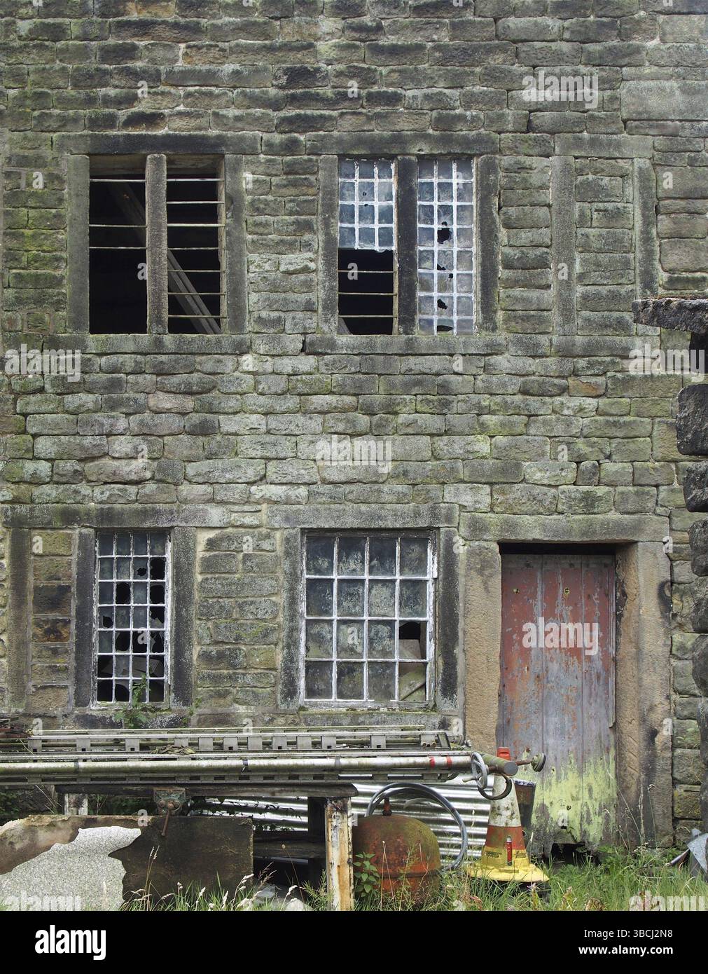 The facade of an old derelict stone house with broken windows and ...