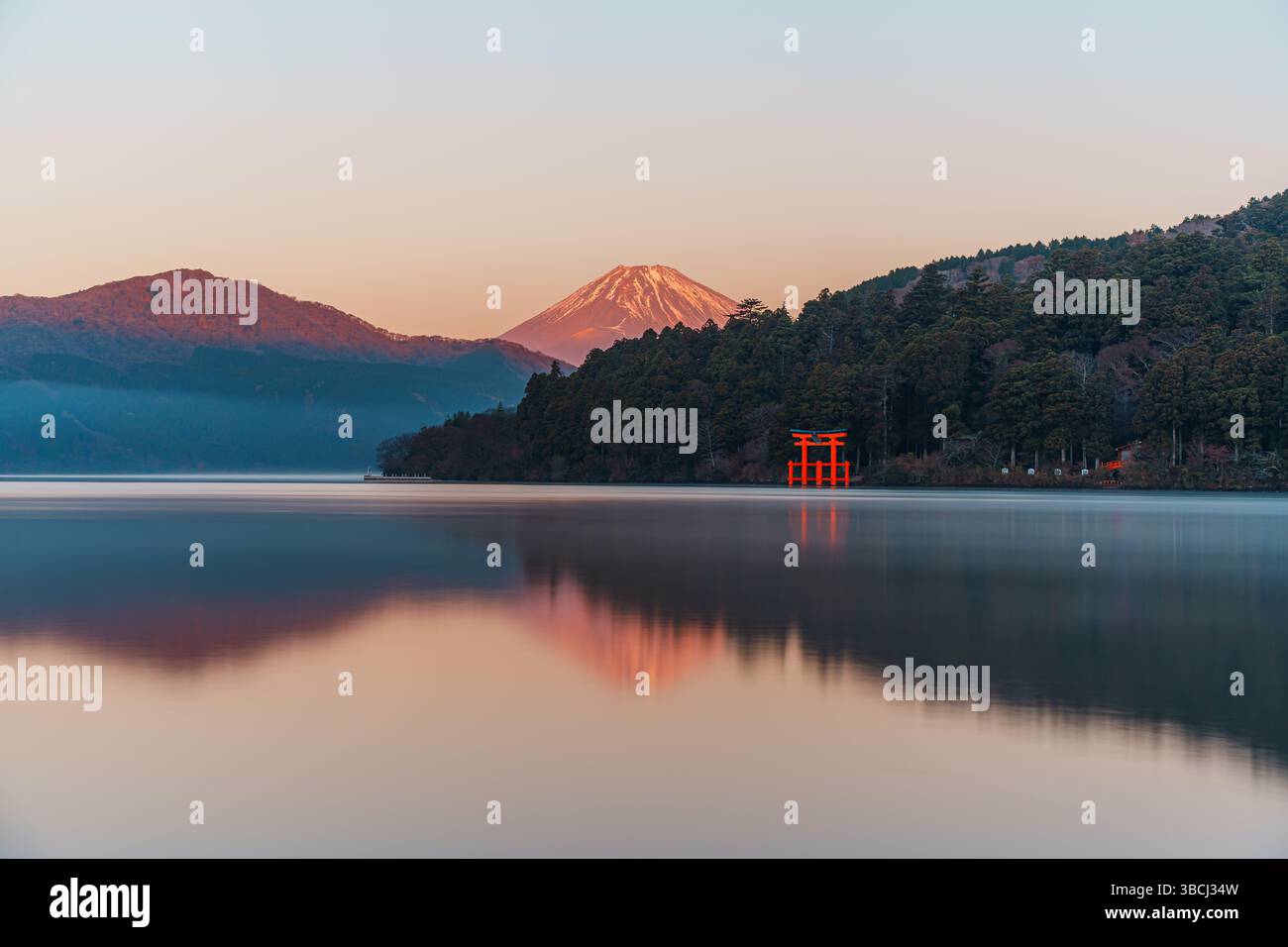 Scenic view of Mount Fuji behind lush forest and iconic red torii gate ...