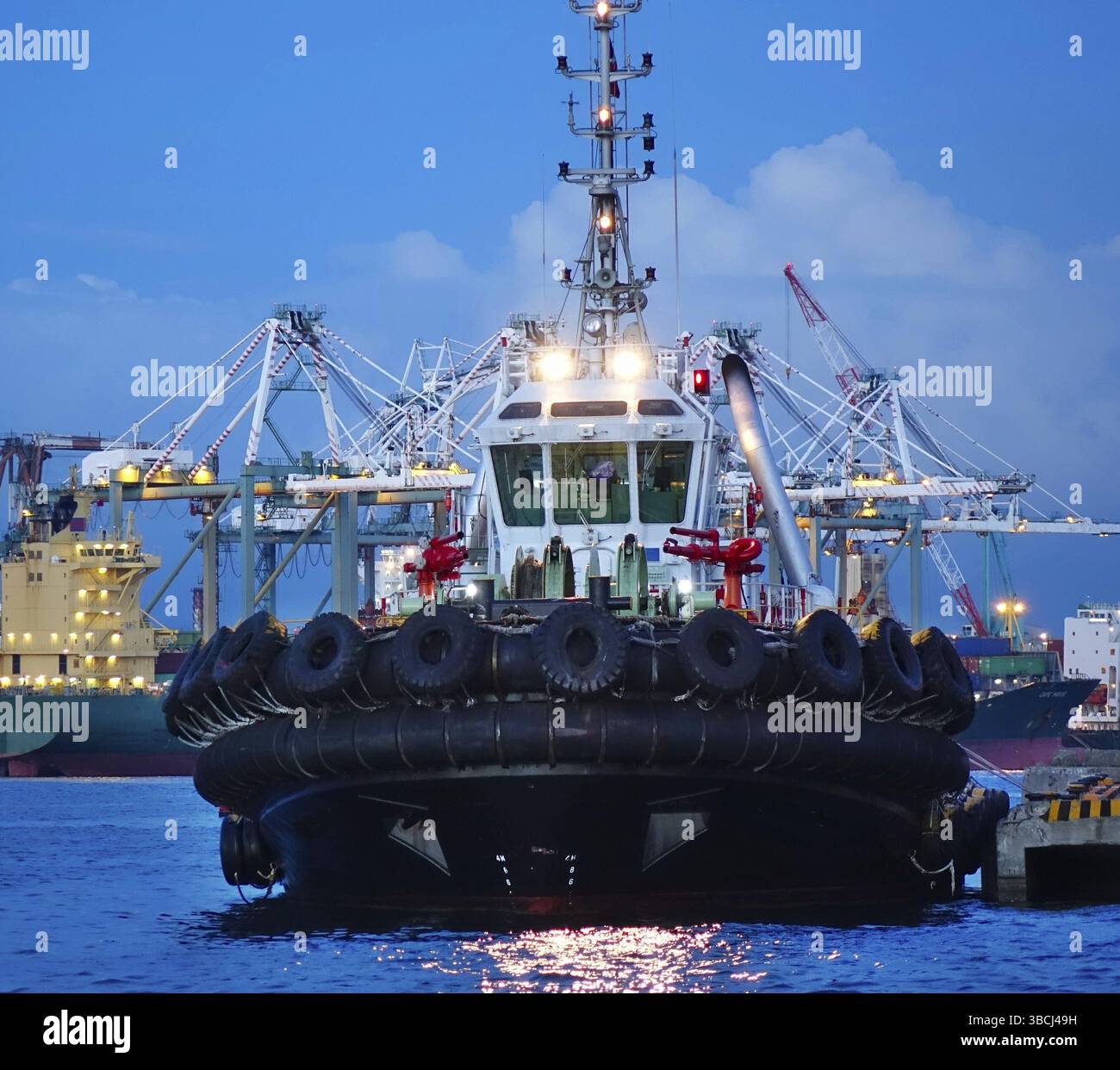 A single tugboat with massive tires fastened to the hull at evening ...