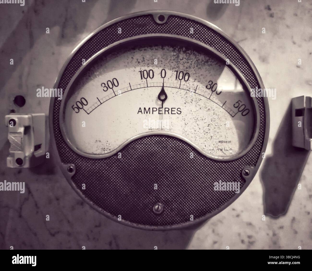 Monochrome image of an old round metal industrial ammeter with an ...