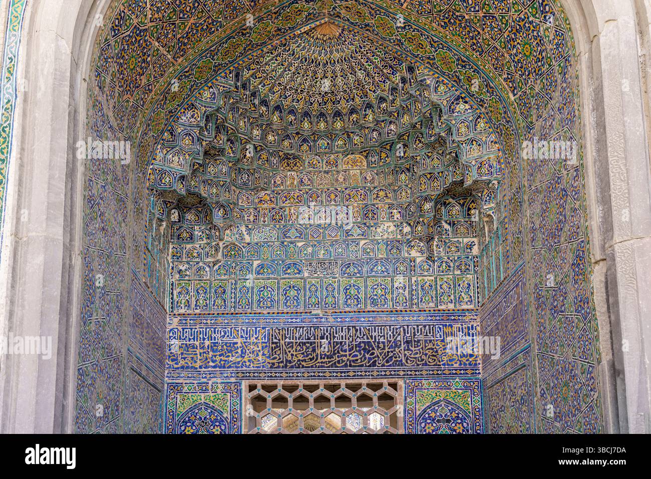 An ornate muqarnas ceiling with gold and blue tiles decorates the ...