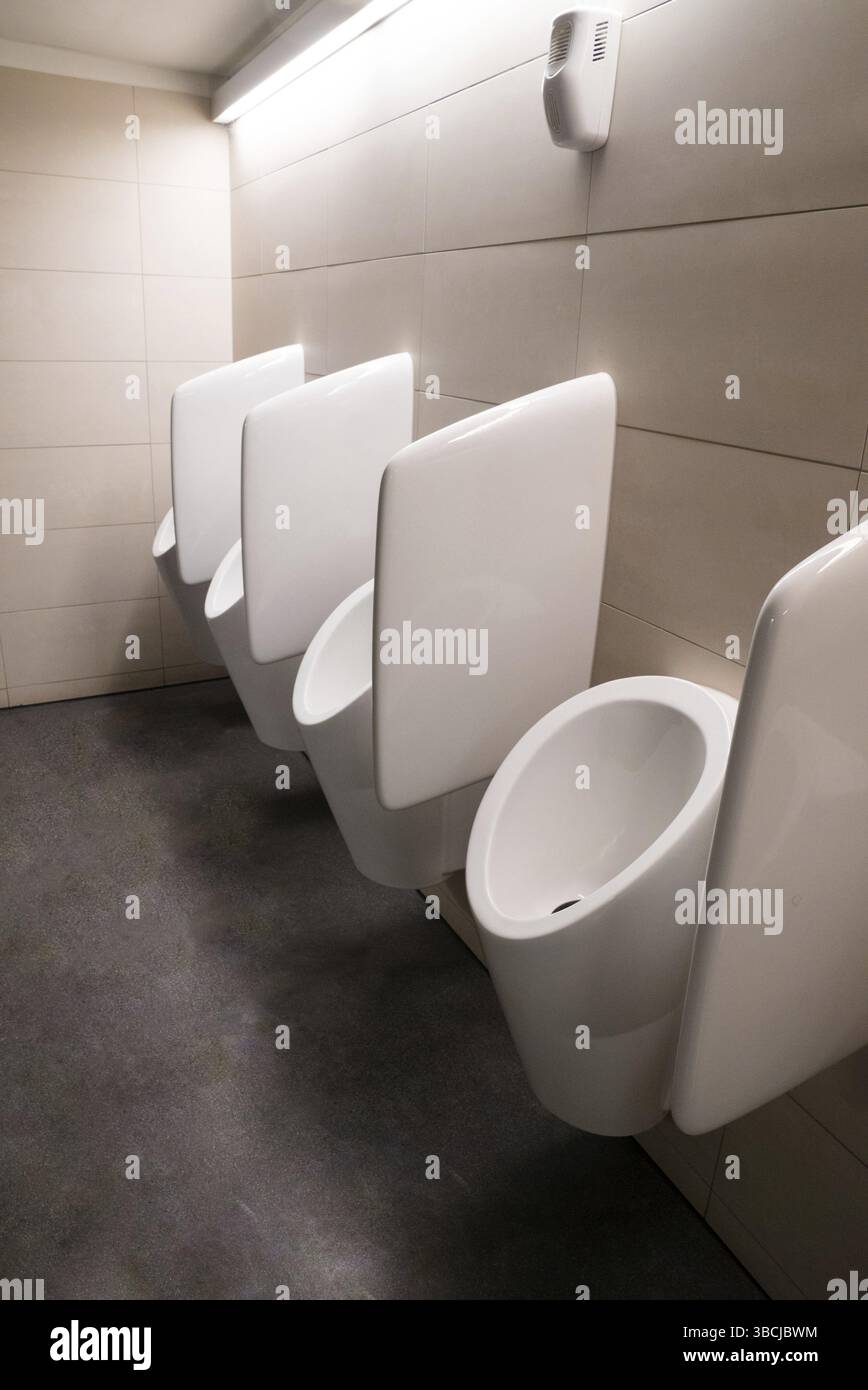 clean white modern ceramic urinals in a modern public toilet for men ...