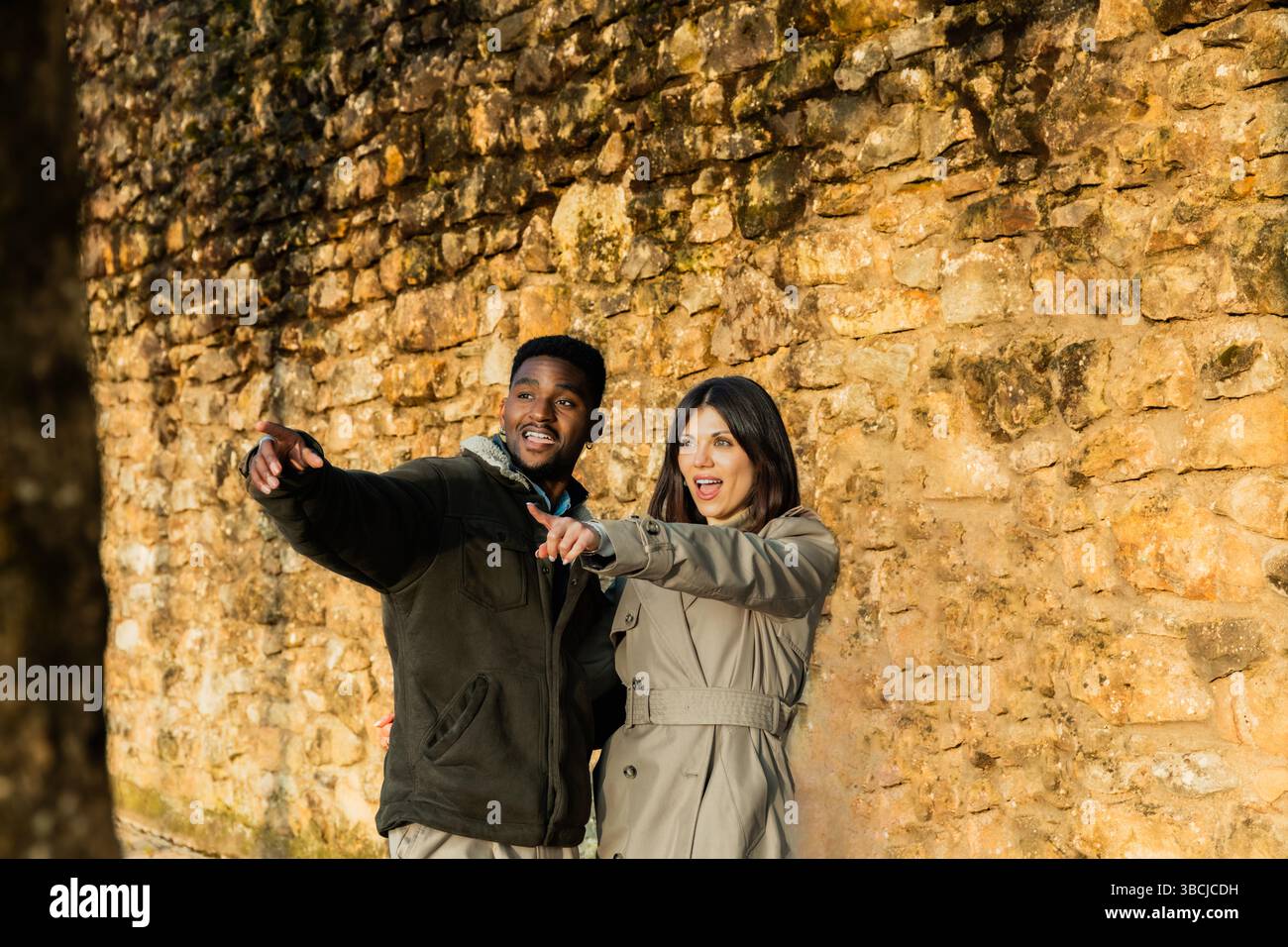 A cheerful couple enjoys a moment together, pointing and laughing as ...