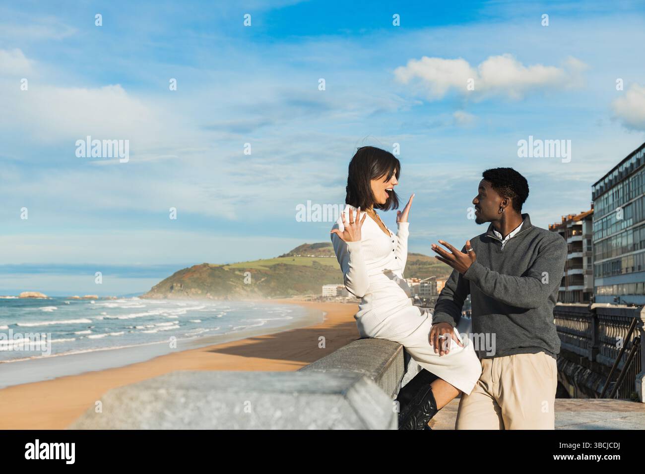 A couple engaged in an animated conversation on a beachfront promenade ...