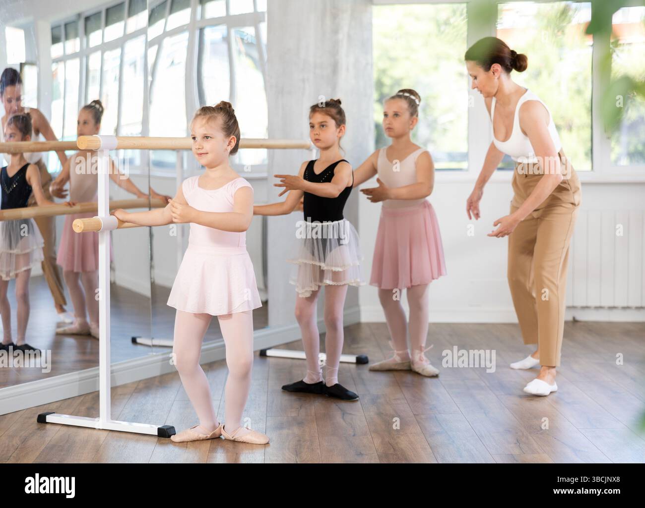 Woman teacher corrects girls in plie movement Stock Photo - Alamy