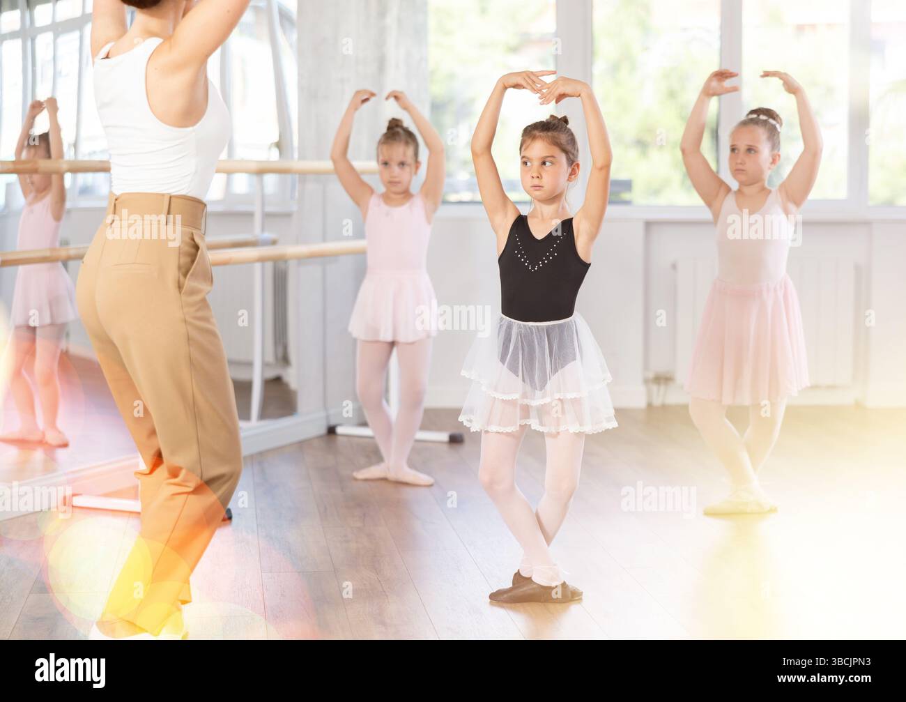 Girl students of choreographic school look at woman teacher and repeat ...