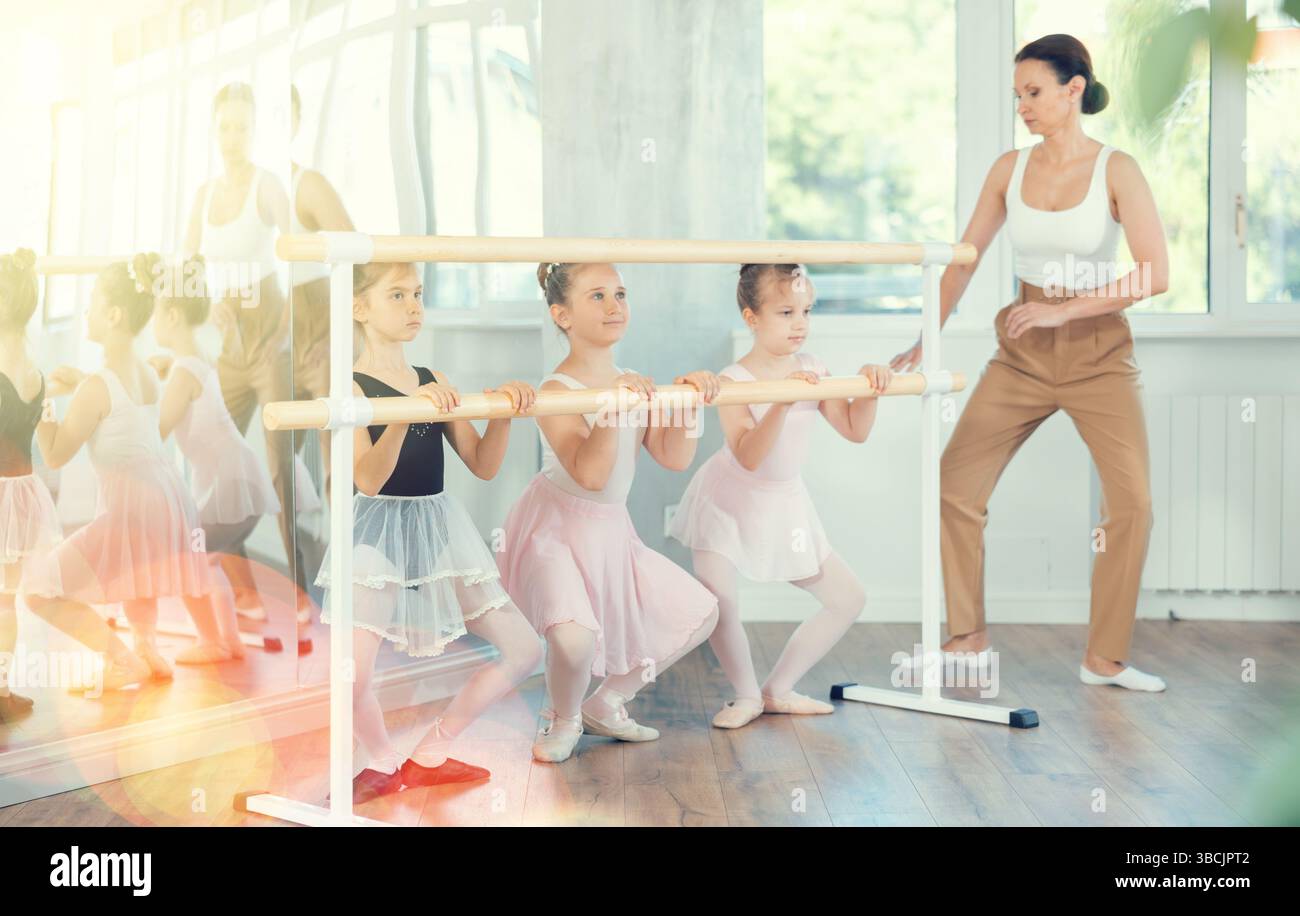 Woman teacher corrects girls in plie movement Stock Photo - Alamy