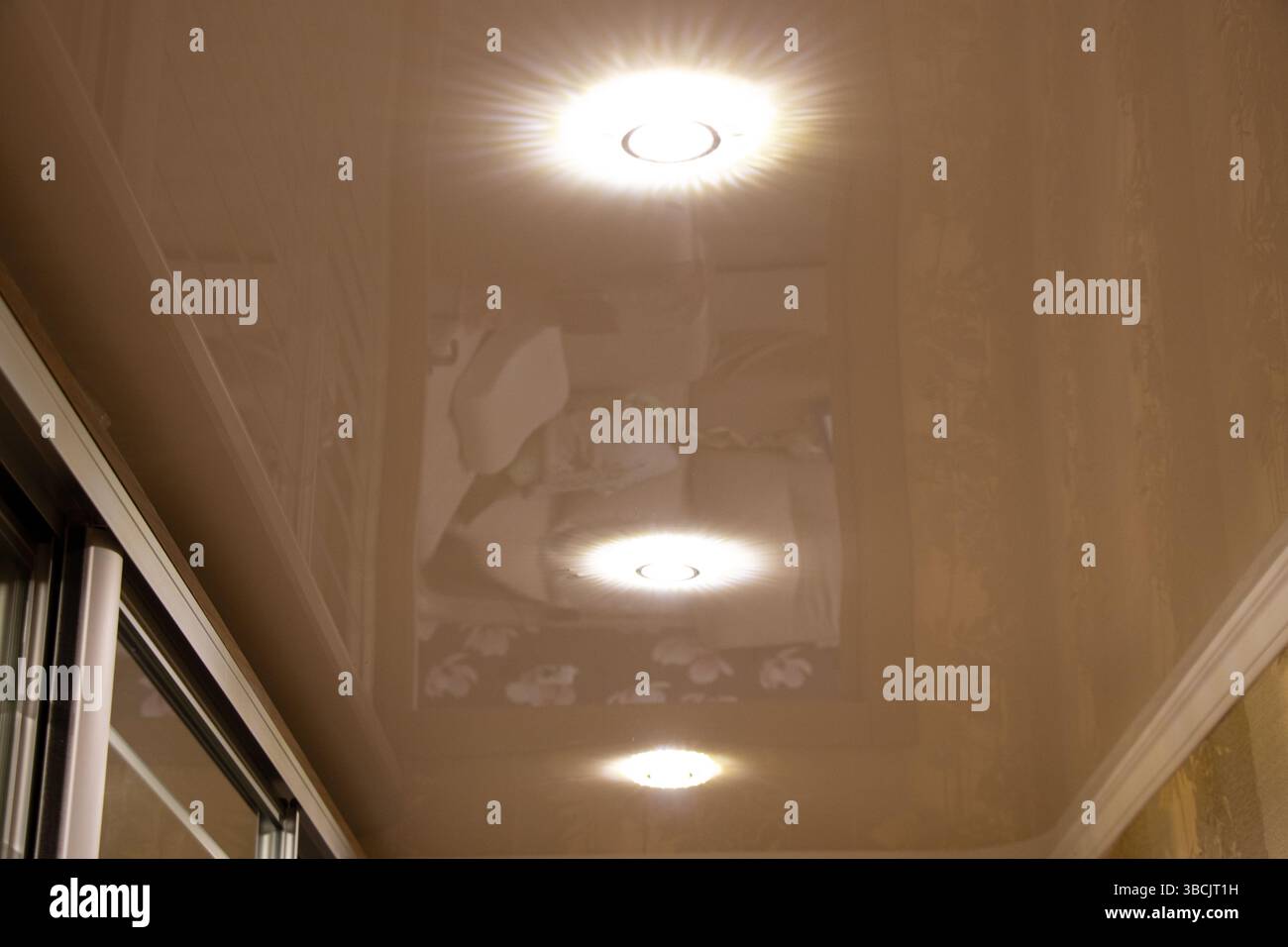 Stretch beige ceiling with three light bulbs shining in the hallway in ...