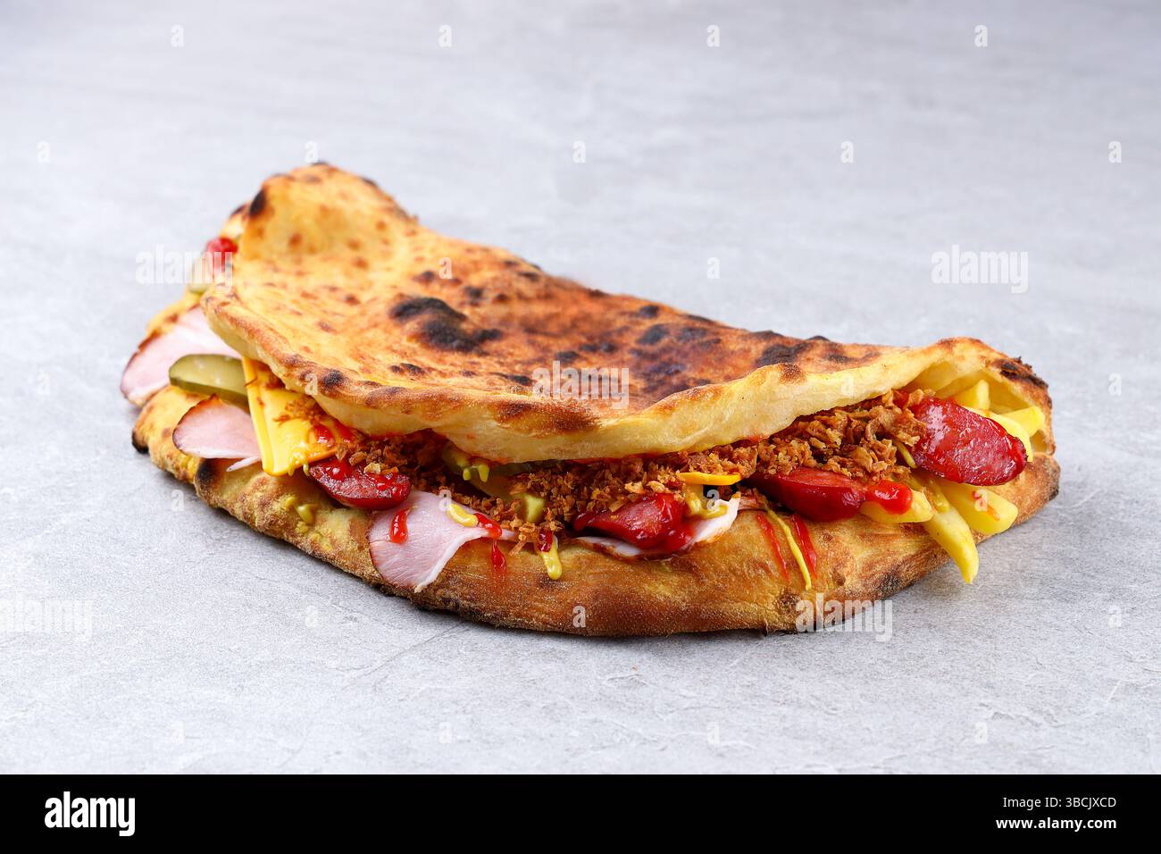 Rustic folded pizza sandwich stuffed with smoked ham, spicy sausage ...