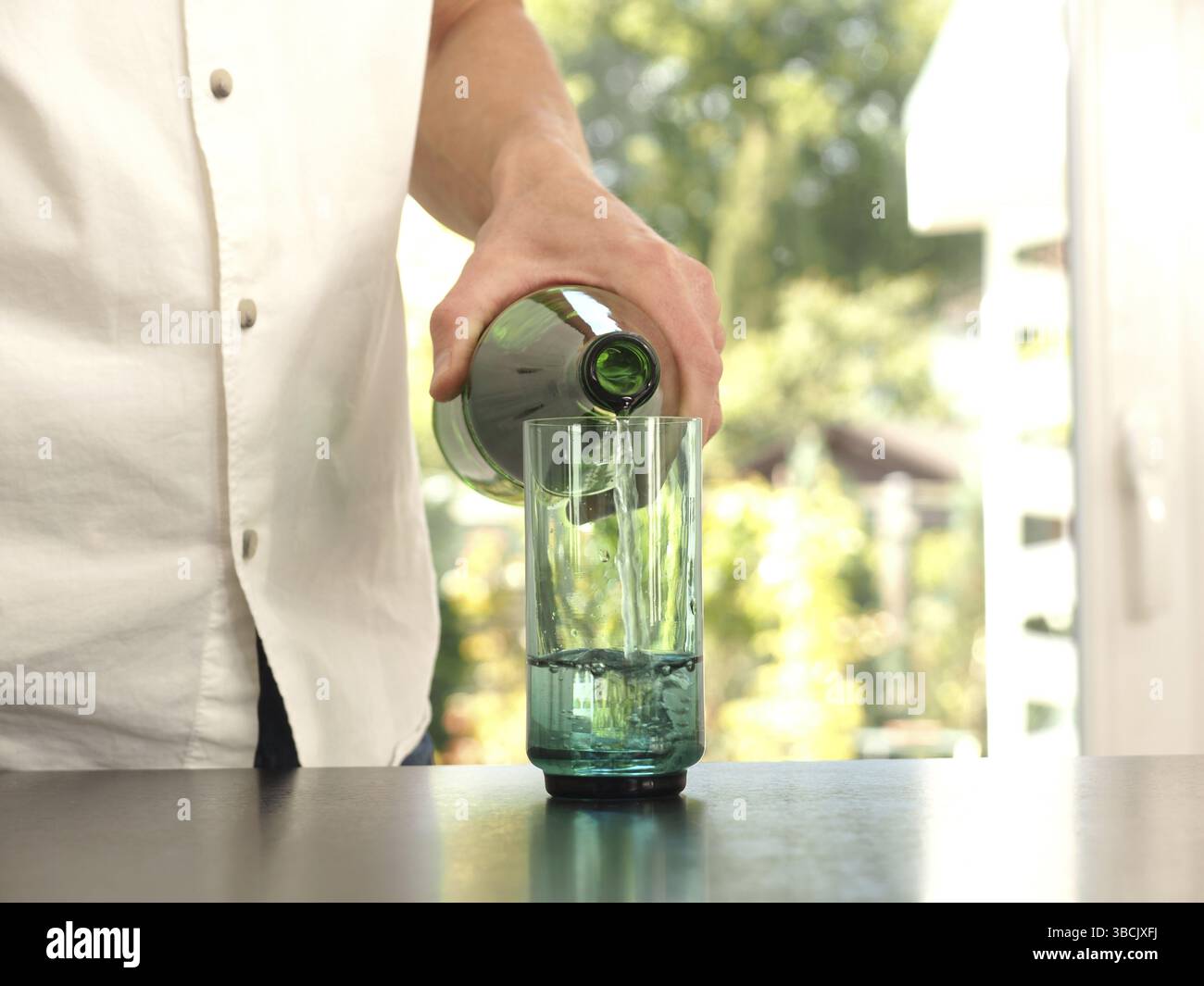 Mid aged man pouring water into a glass, healthy eating concept, clean ...