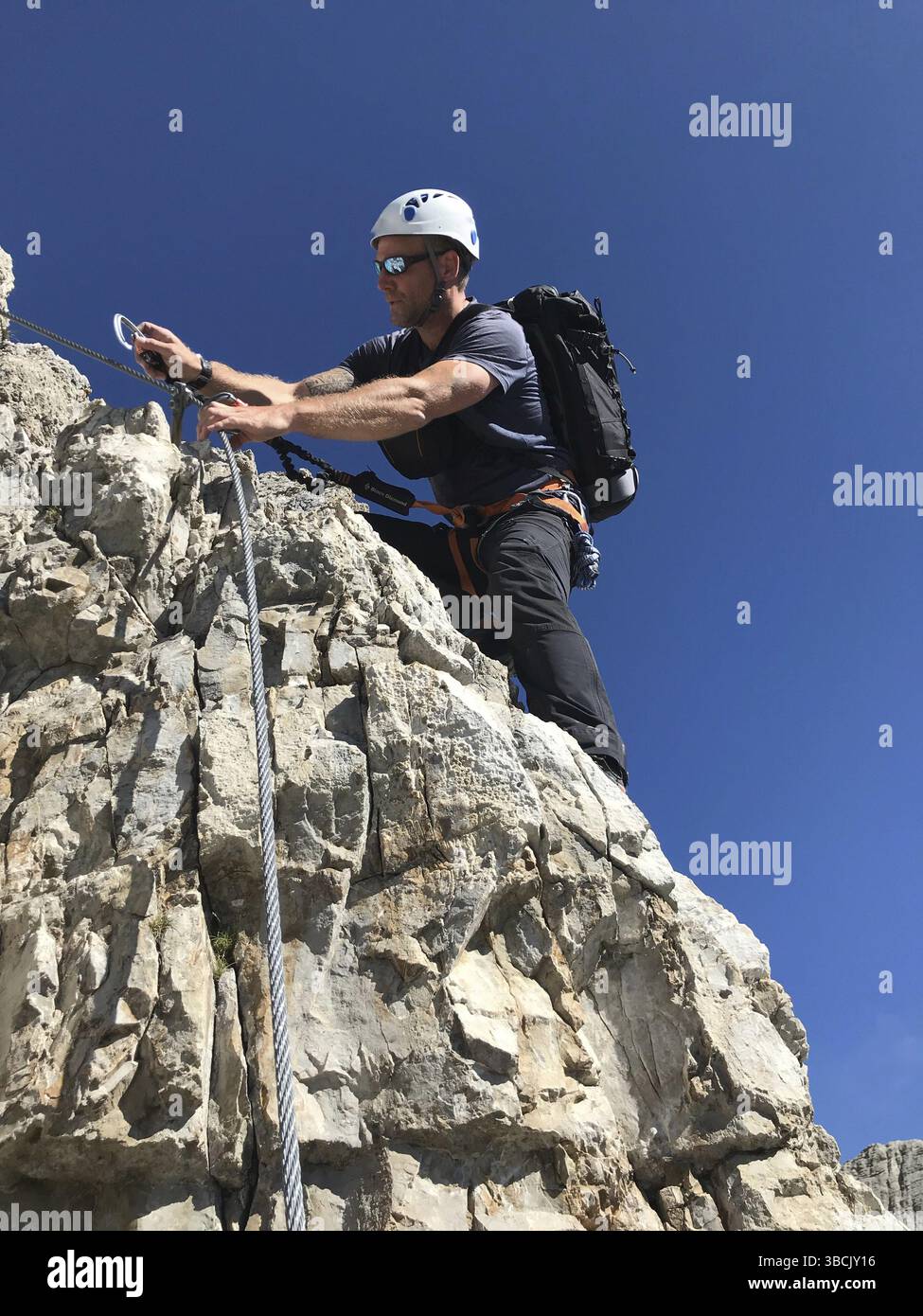 mountain guide on a steep and exposed Via Ferrata in Alta Badia in the ...