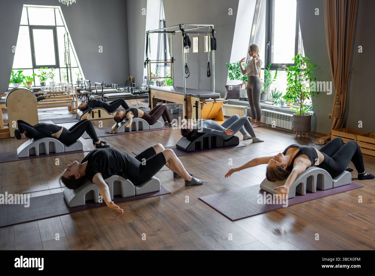 Group of women doing exercises on back spine corrector. Reformer ...