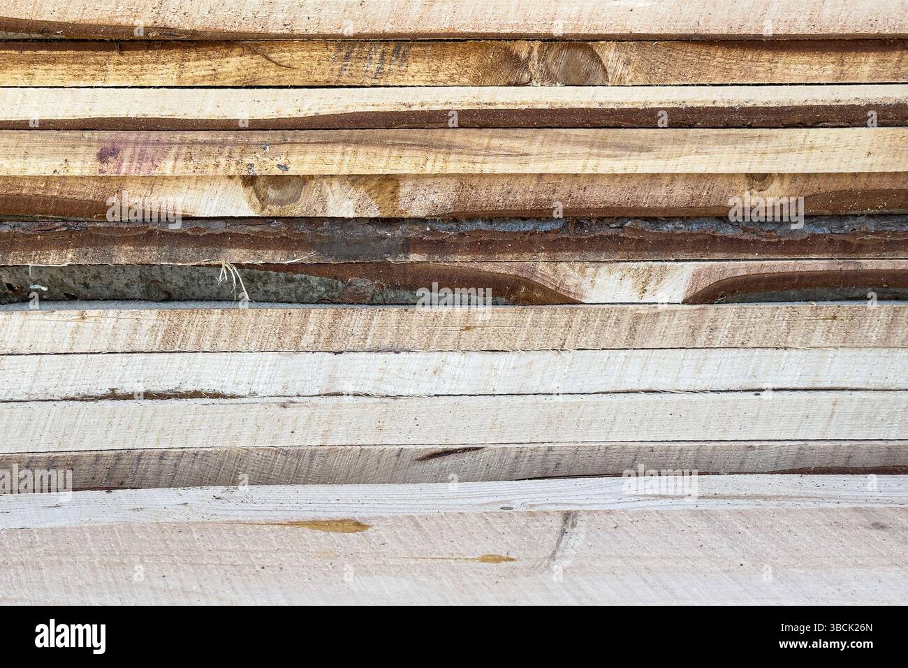 Close-up of rough sawn timber planks with bark and wood grain texture ...