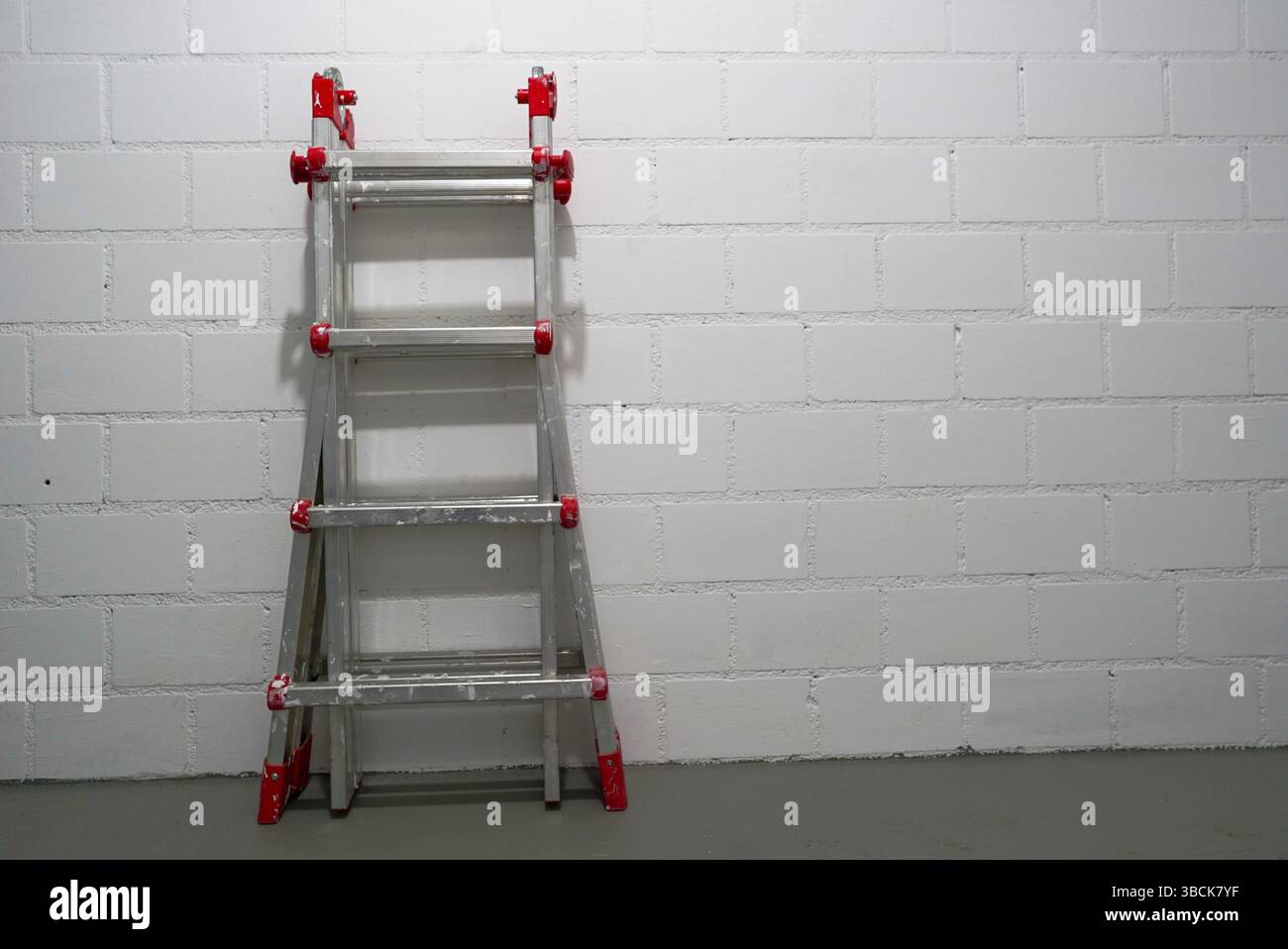 An aluminum metal ladder with old paint in a simple cellar room with ...