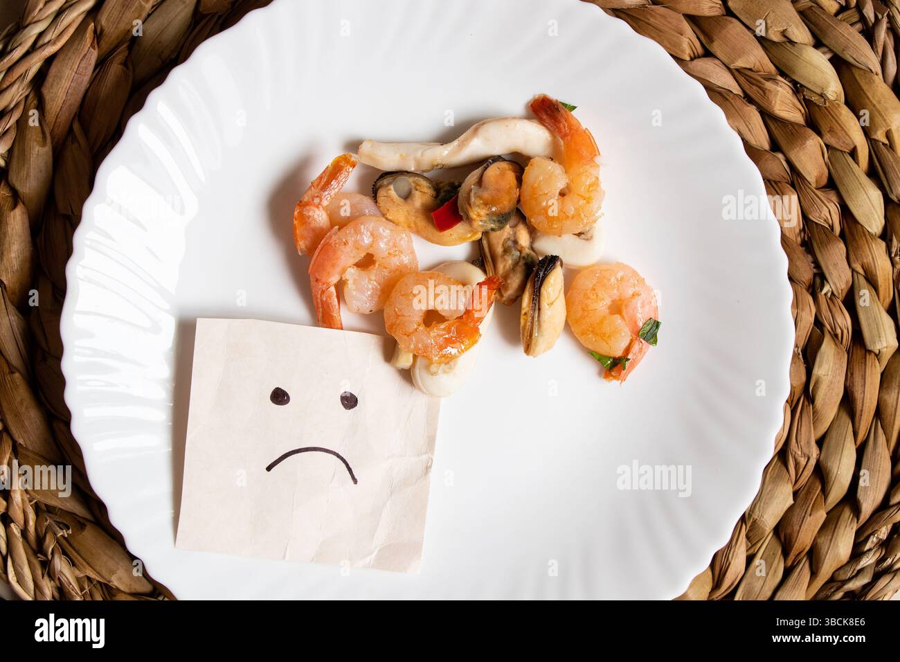 Seafood shrimp and squid are lying on a plate and a sad smiley face is ...