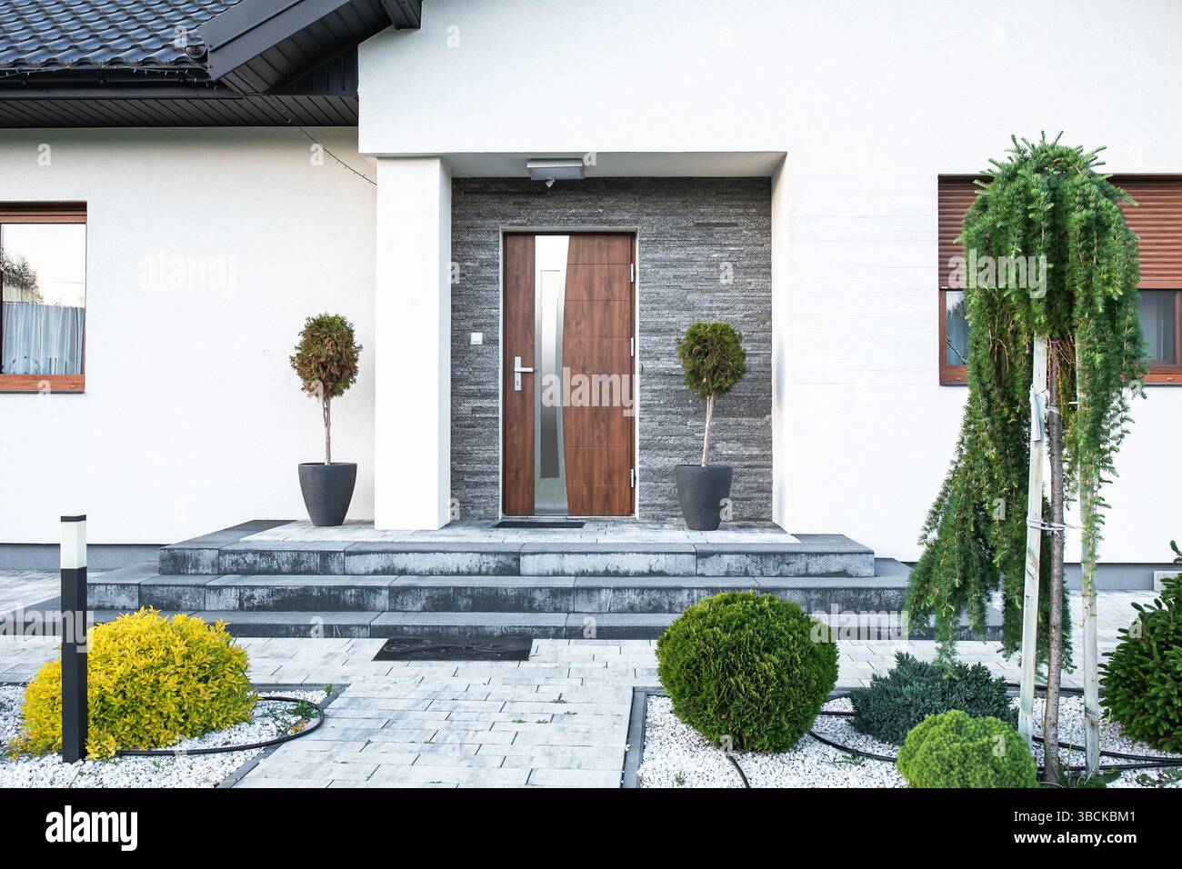 A front door detail with a stone accent wall, a brown door, covered ...