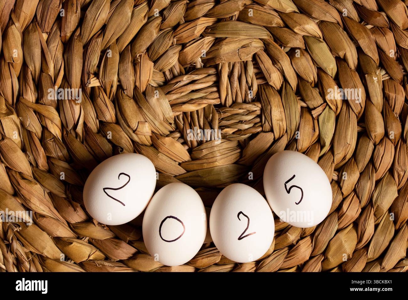 Eggs with the inscription 2025 lie on a straw wicker brown background ...
