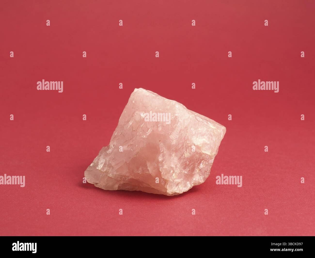 Rose quartz rough stone on a red background, minerals or healing stones ...