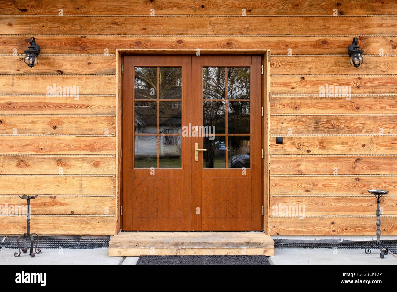 A front door detail with a stone accent wall, a brown door, covered ...