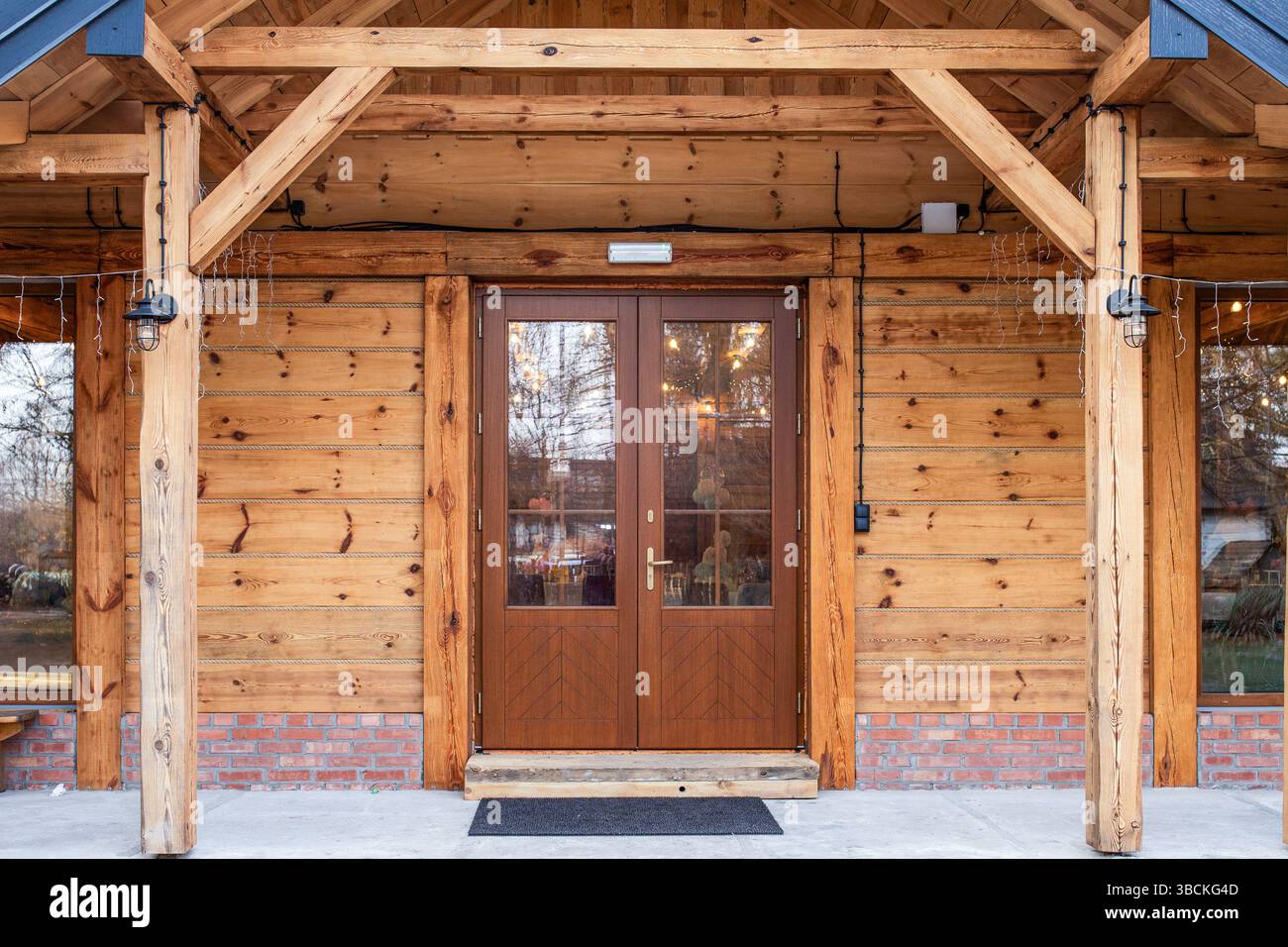 A front door detail with a stone accent wall, a brown door, covered ...